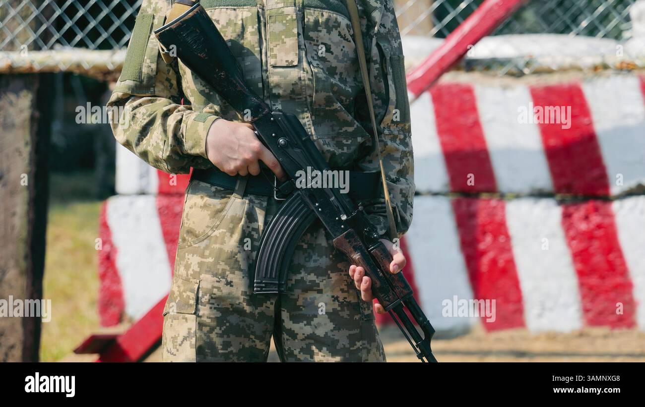 Soldier Holding Rifle in Front of Red and White Barrier. A soldier in ...