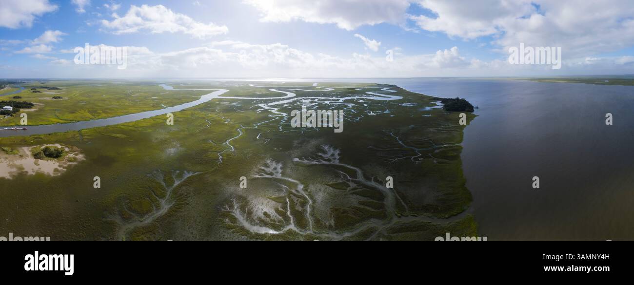 Aerial view of serene wetlands and river under a clear sky with clouds ...