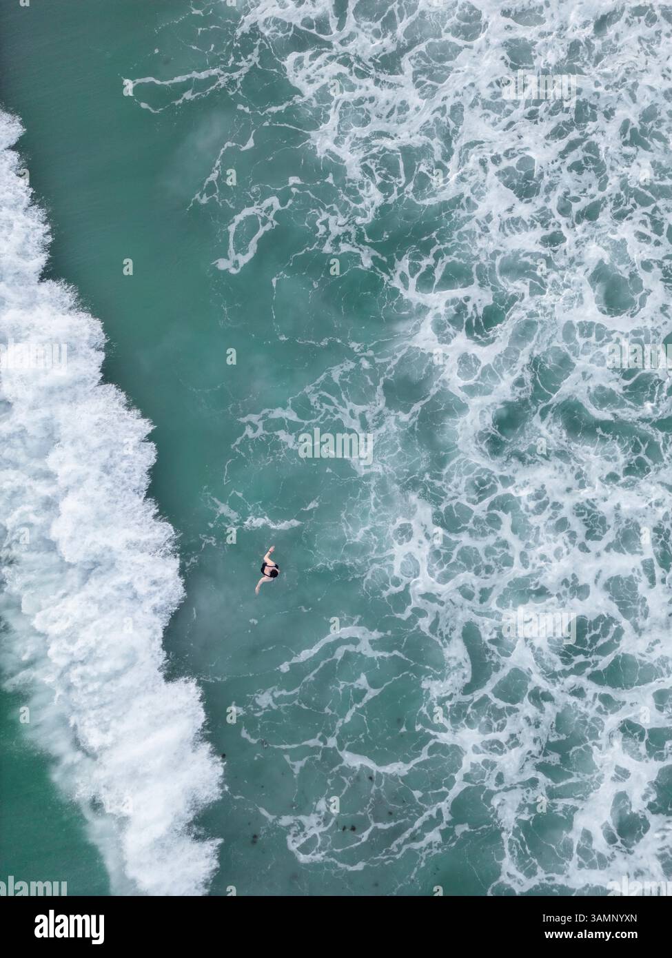 Aerial view of a beautiful tropical coastline with waves and one person ...