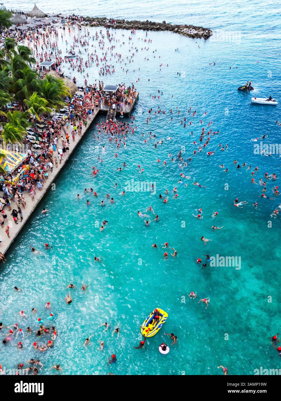 Aerial view of crowded beach with boats and palm trees at Jan Thiel Bay ...