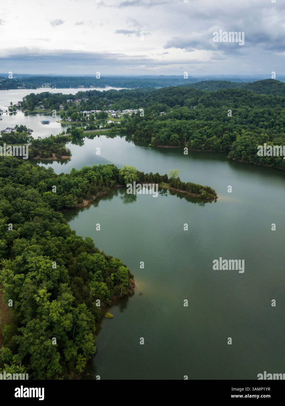 Aerial view of serene lake surrounded by lush forest and rolling hills ...