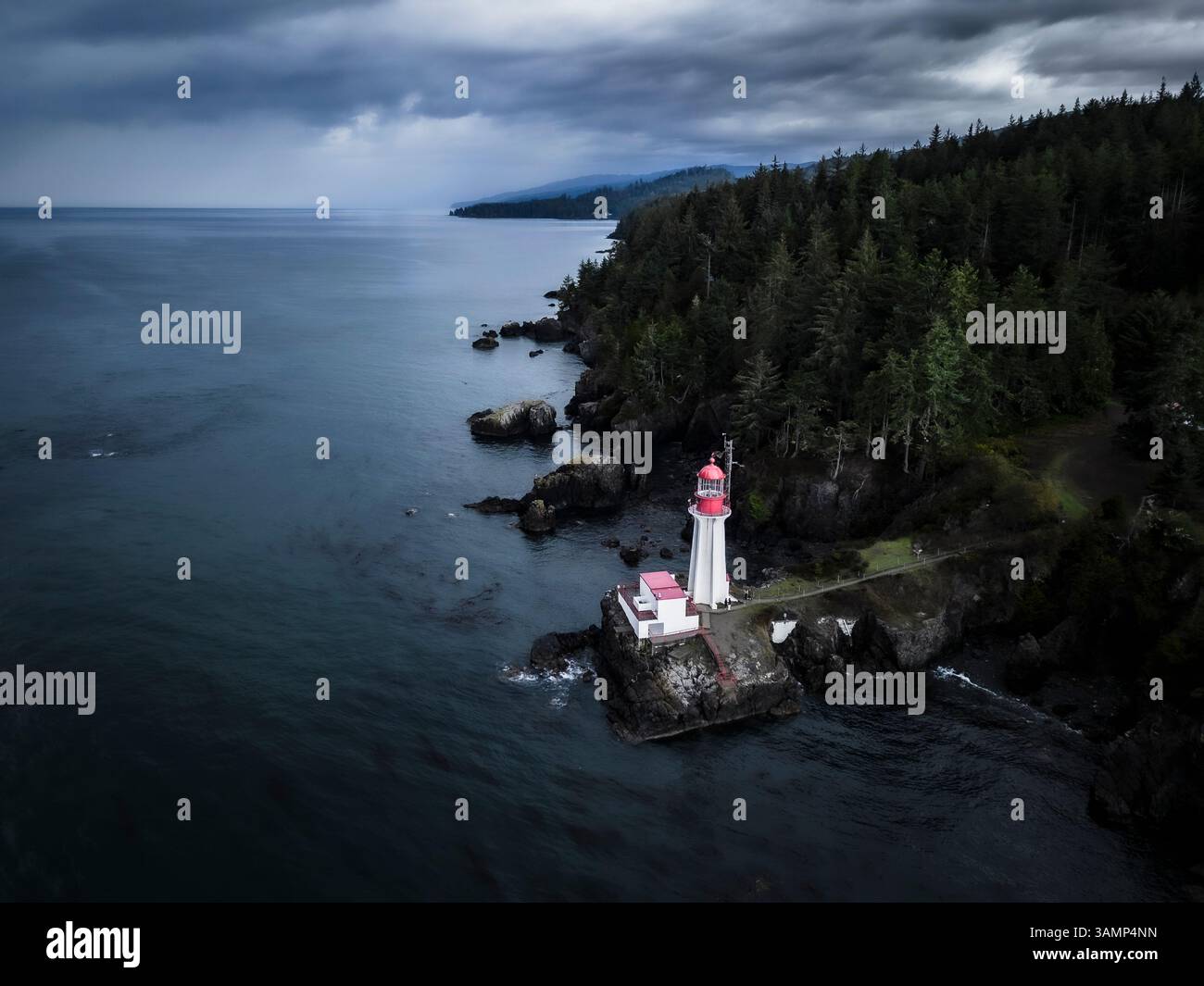 Aerial view of rocky shore with lighthouse overlooking ocean and forest ...