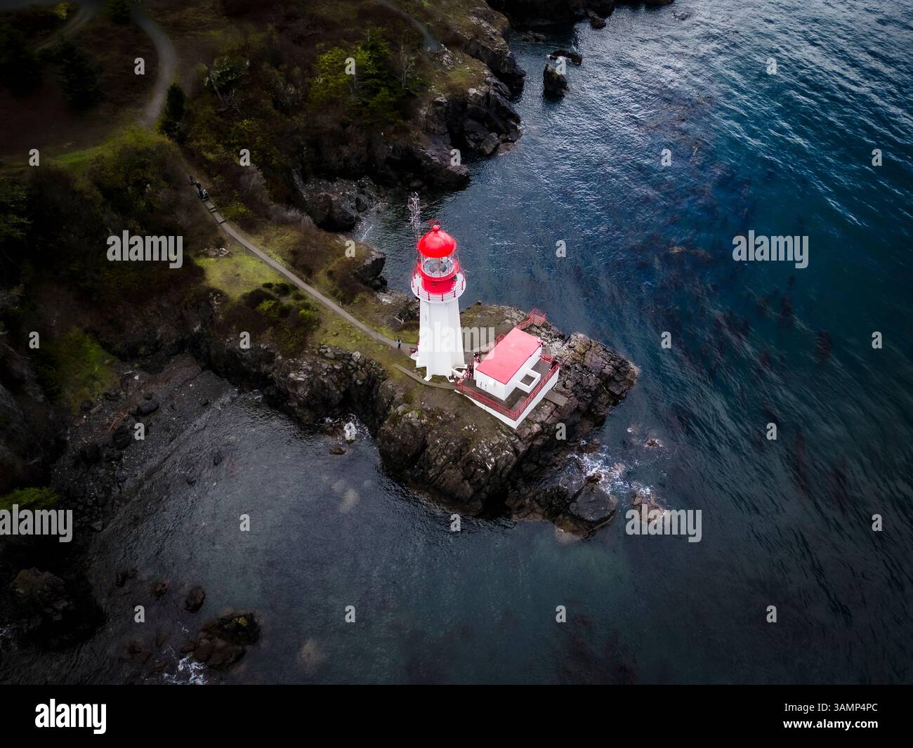 Aerial view of rocky shore with lighthouse overlooking ocean waves ...