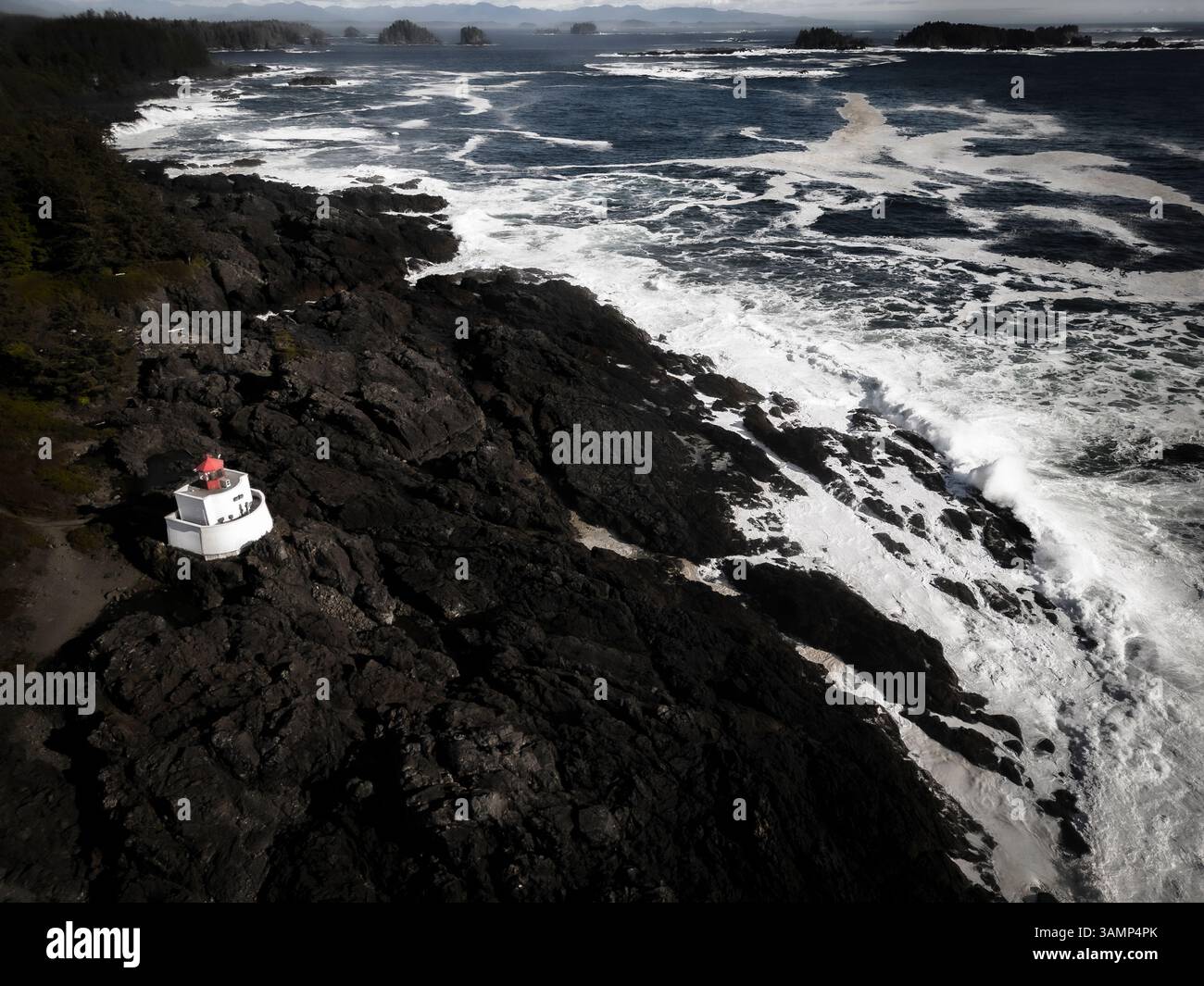 Aerial view of rocky coast with lighthouse overlooking ocean waves ...