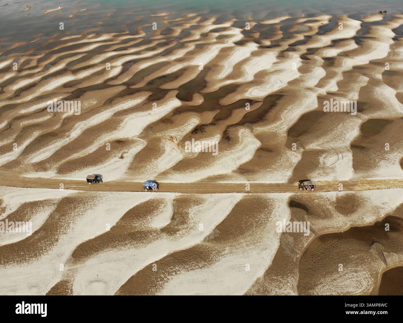 Aerial view of people crossing a golden sandbar with patterns and textures, Sariakandi, Rajshahi ...
