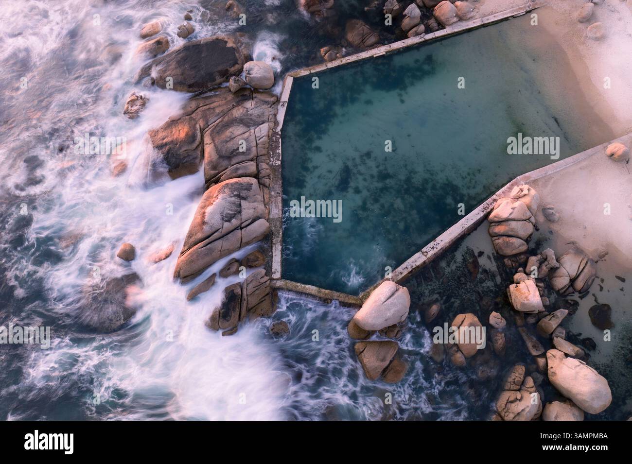 Aerial view of serene tidal pool and rocky shore at sunset, Maidens ...