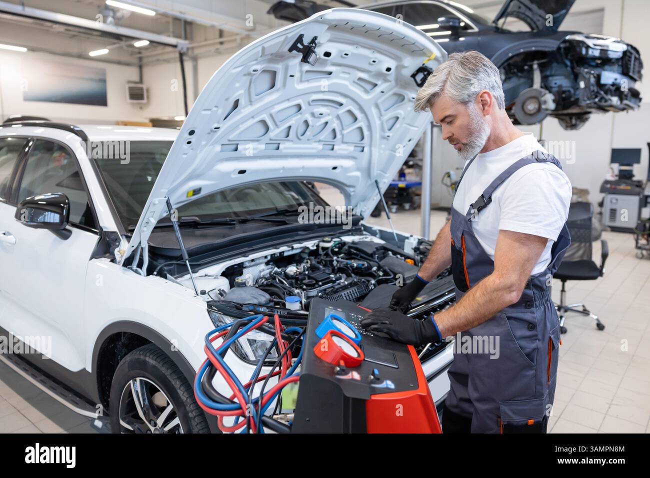 Mechanic in service shop using device measuring heat level in air ...