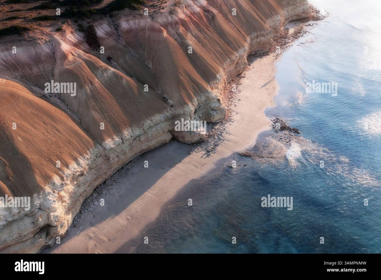 Aerial view of a couple walking on a beach with limestone cliffs ...