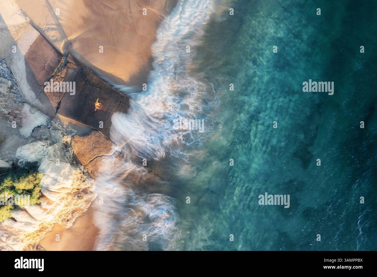 Aerial view of two people standing on a beach boat ramp at sunset ...