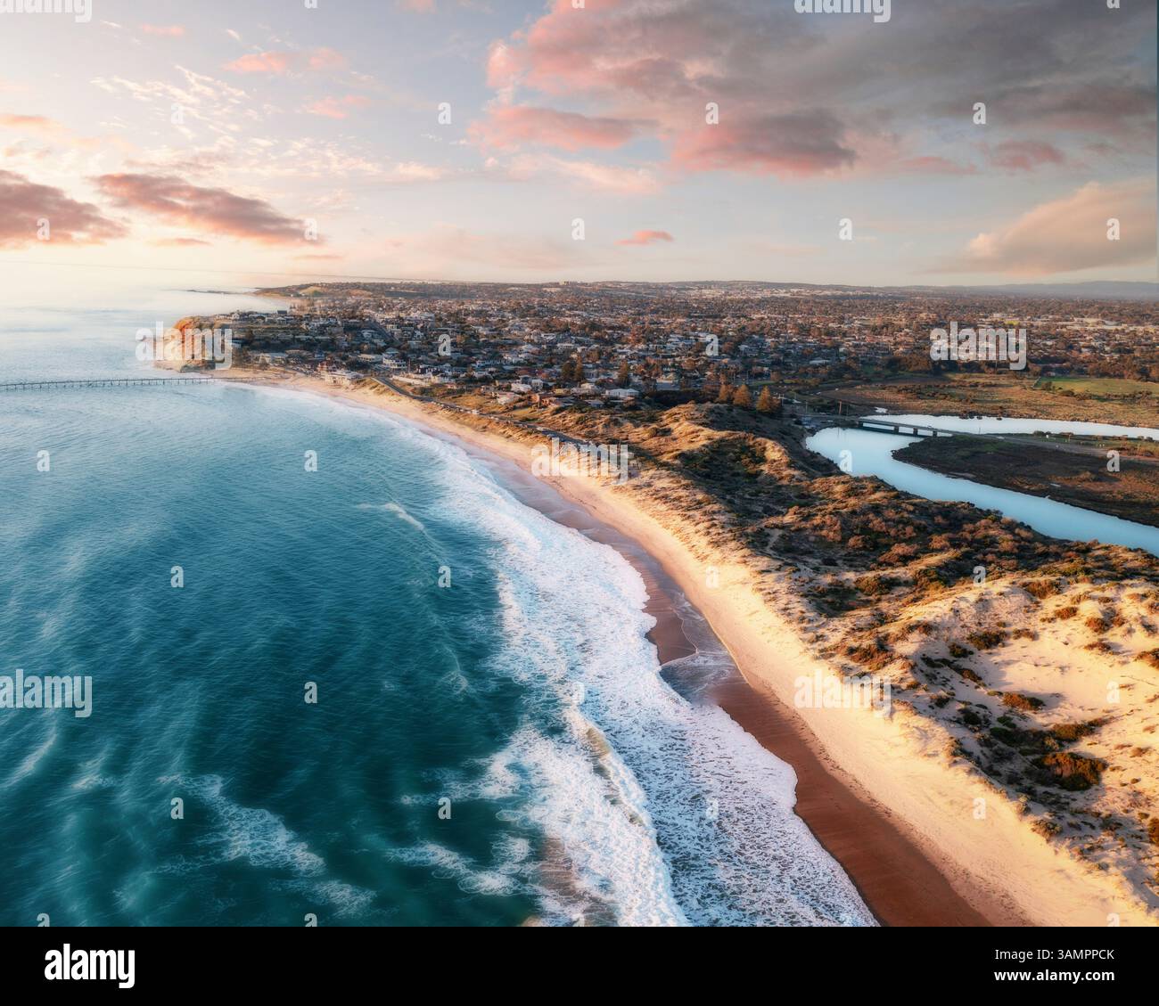 Aerial view over a long sandy stretch of beach during sunset, with blue ...