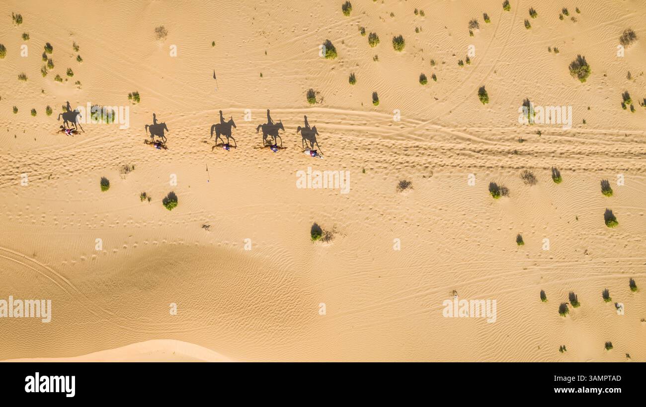 Aerial view of people riding camels in the desert of Al Khatim in Abu ...