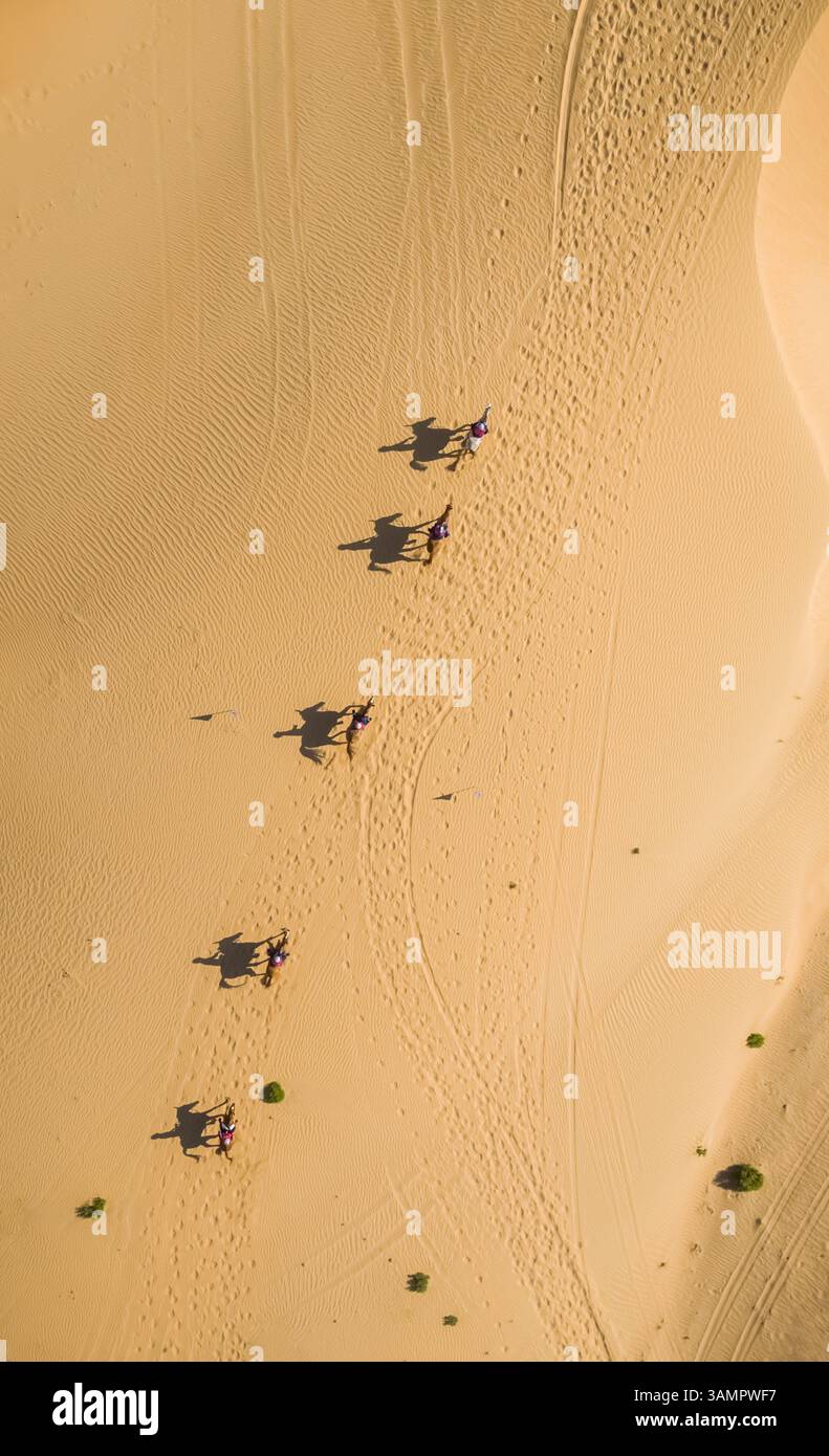 Aerial view of people riding camels in the desert of Al Khatim in Abu ...