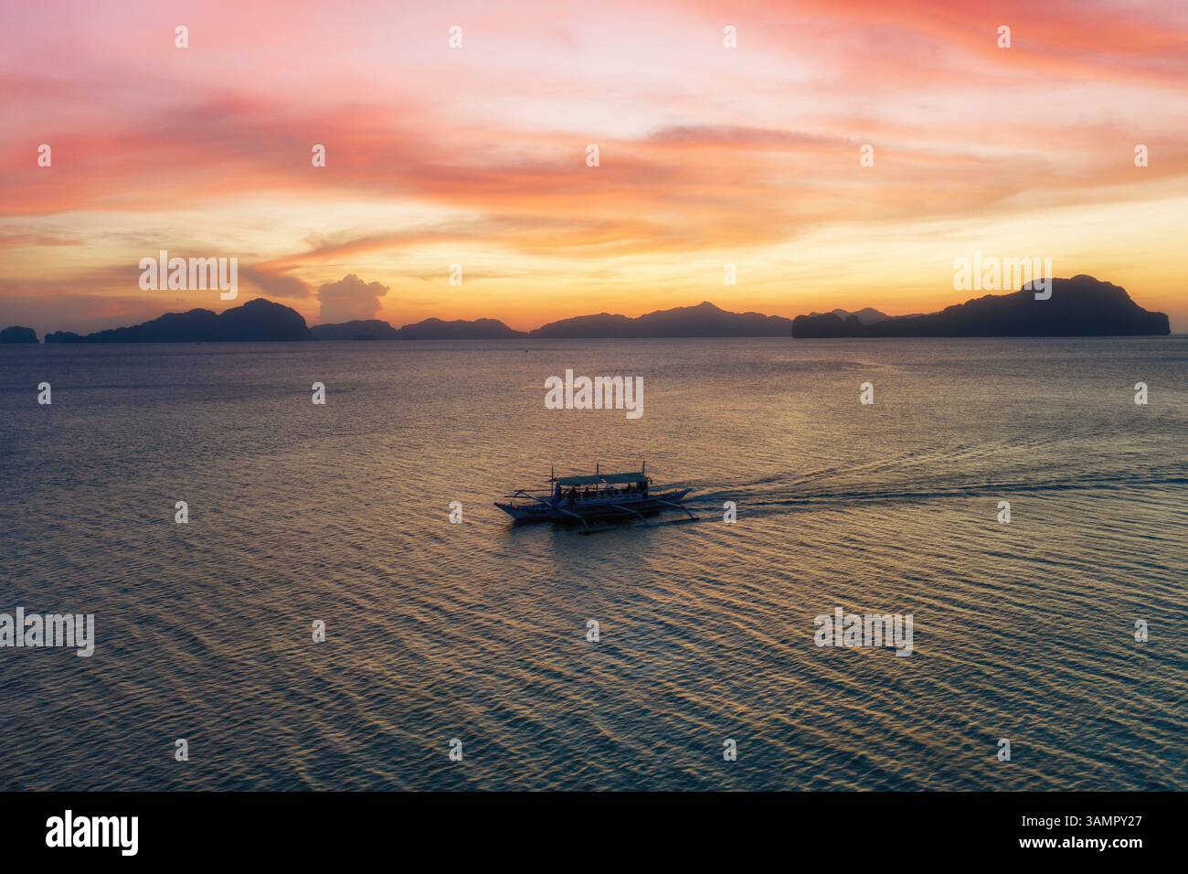 Aerial view of a passenger boats sailing at sunset across El Nido Bay ...