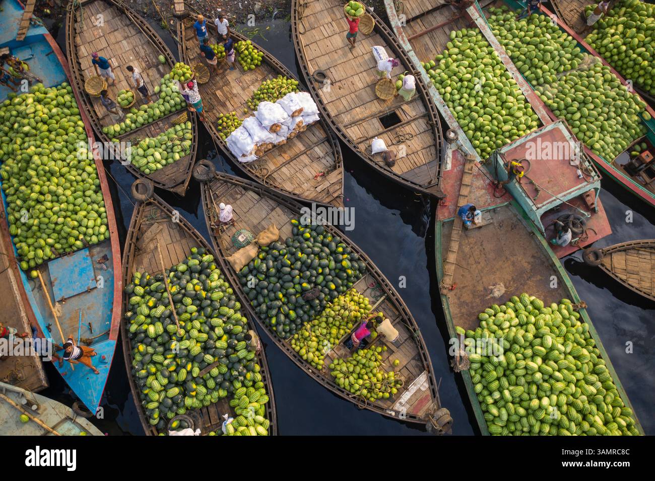 Aerial view of several small commercial boats with people unloading watermelons at Old Dhaka ...