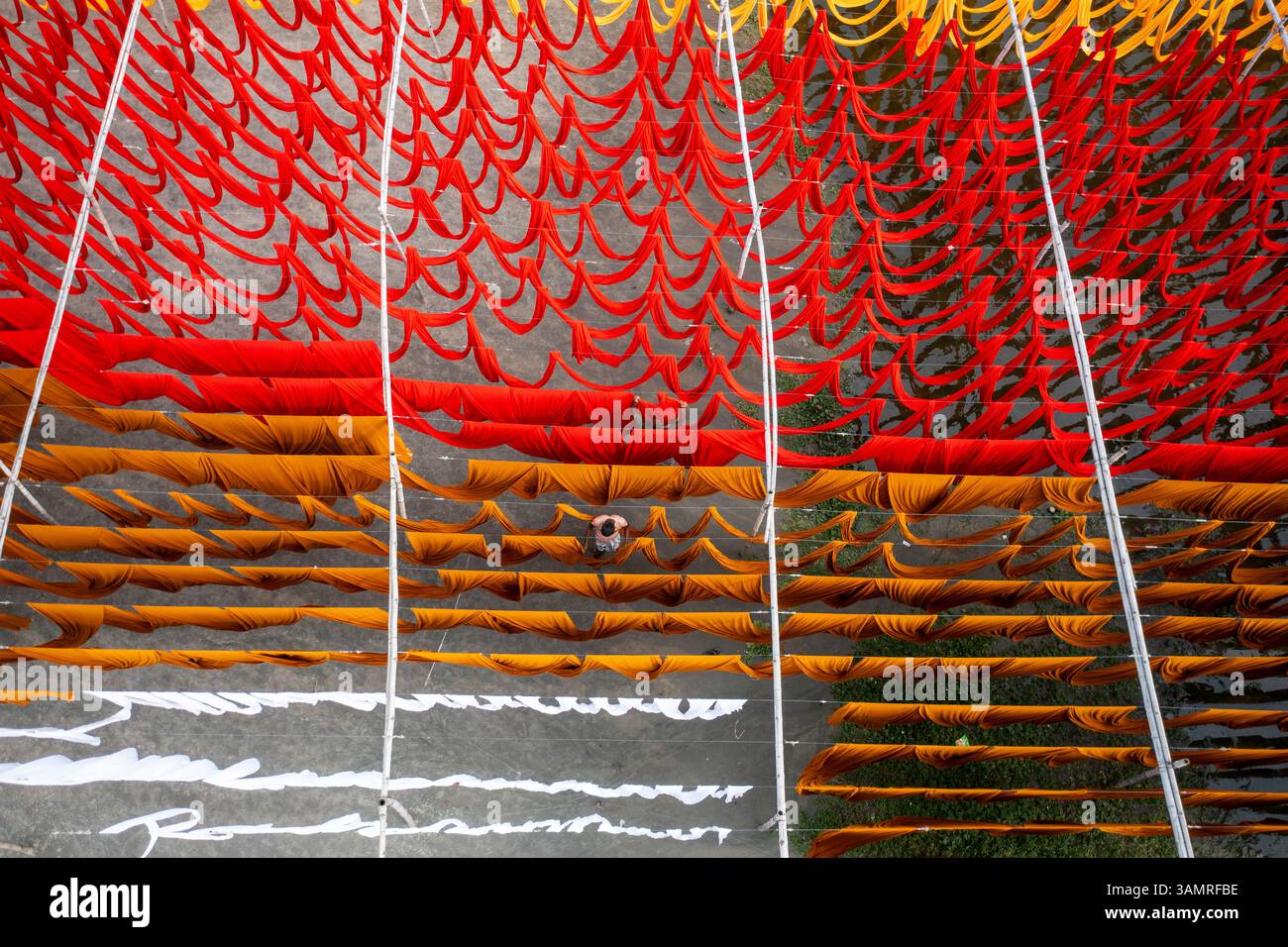 Aerial view of colorful fabric drying in rows under sunlight at a ...