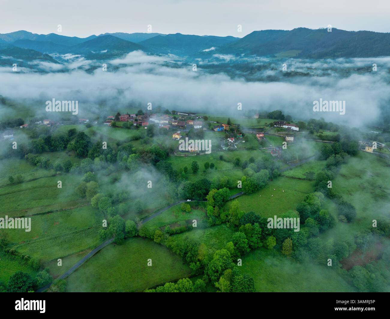 Aerial view of misty village surrounded by greenery and mountains, Infiesto, Asturia, Spain ...