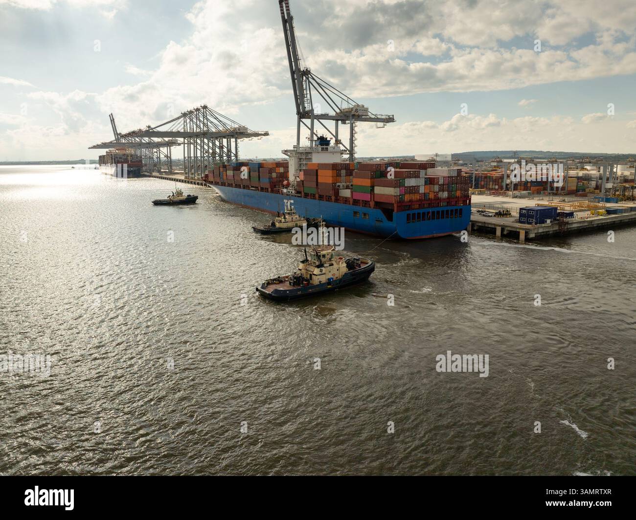 Tug Boats Push A Container Ship Into Dock Stock Photo - Alamy