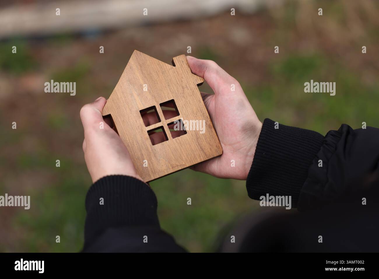 Homeless man with wooden house figure outdoors, closeup Stock Photo - Alamy