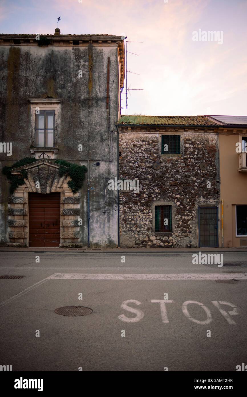 Rustic building façade with a visible stop sign painted on the road ...