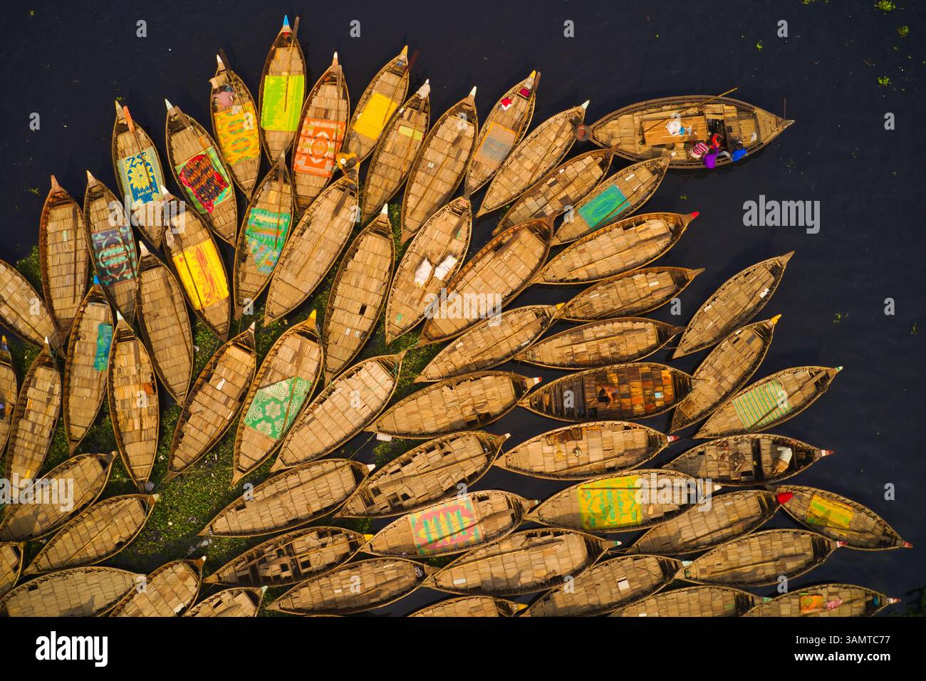 Aerial view of traditional fishing boats among docked ferry boat along Buriganga river in ...