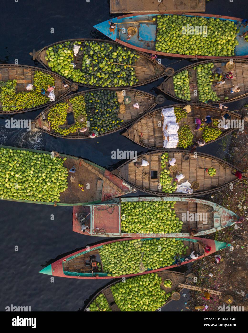 Aerial view of several small commercial boats with people unloading watermelons at Old Dhaka ...
