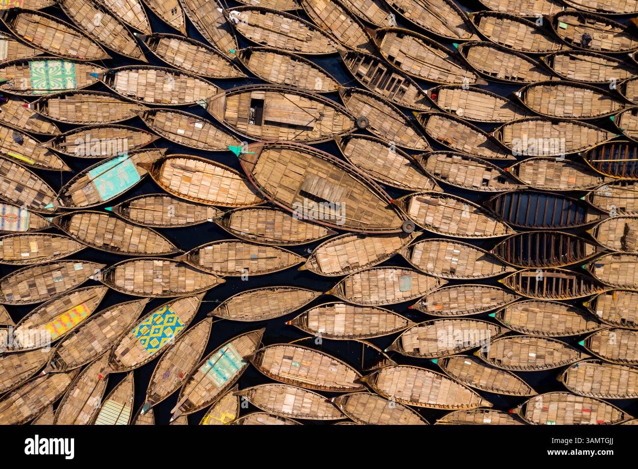 Aerial view of traditional fishing boats among docked ferry boat along Buriganga river in ...