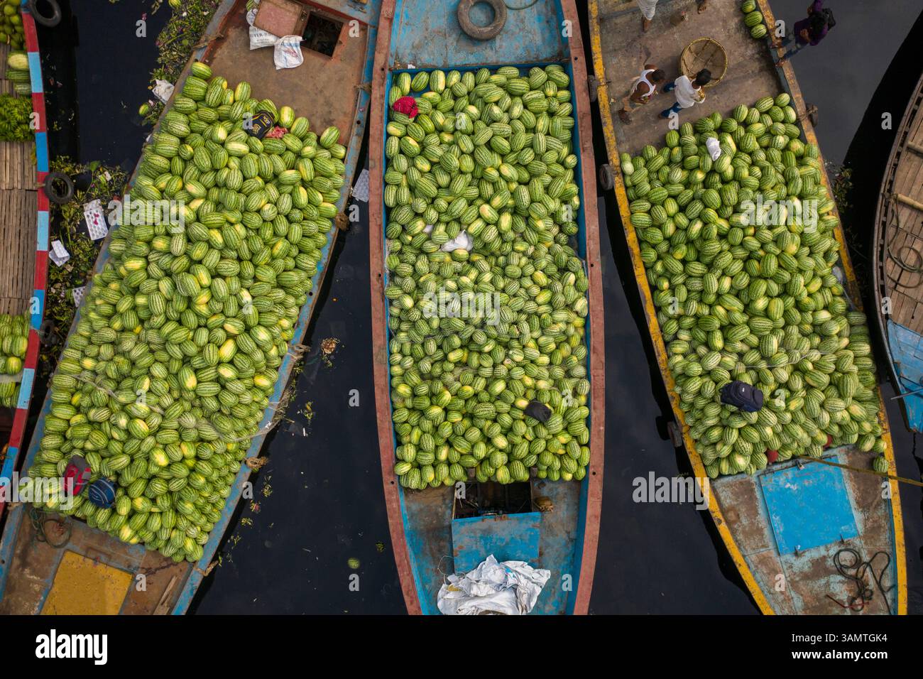 Aerial view of several small commercial boats with people unloading watermelons at Old Dhaka ...