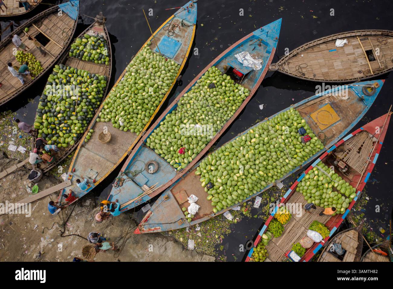 Aerial view of several small commercial boats with people unloading watermelons at Old Dhaka ...