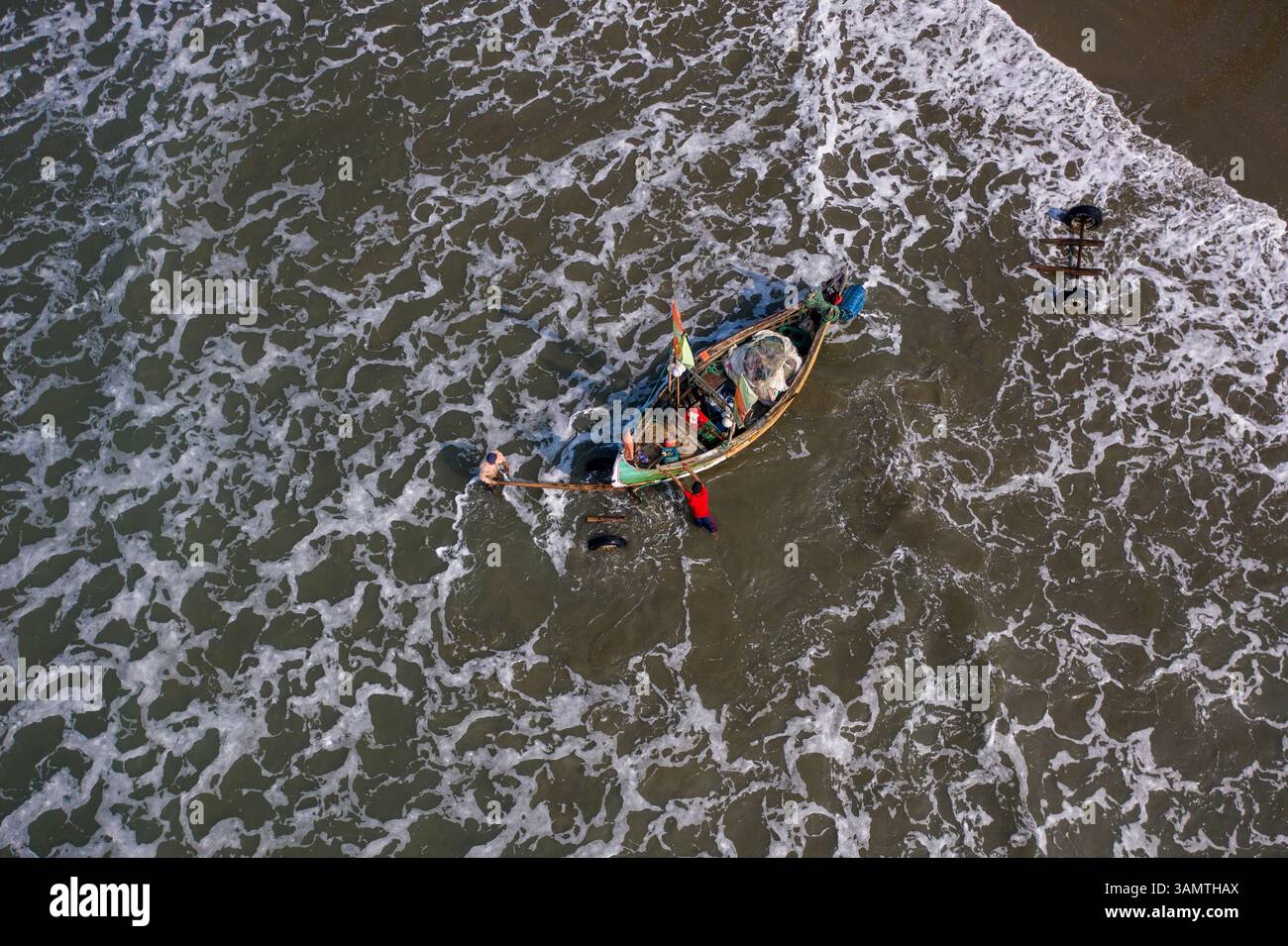 Aerial view of a few people pushing a traditional canoe along the shoreline on St. Martin's ...