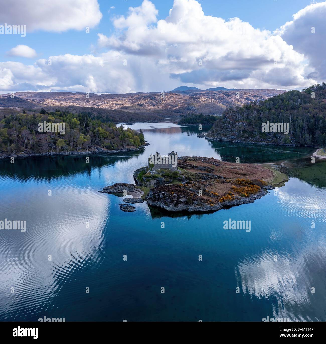 Aerial view of Castle Tioram with serene lake and majestic mountains ...