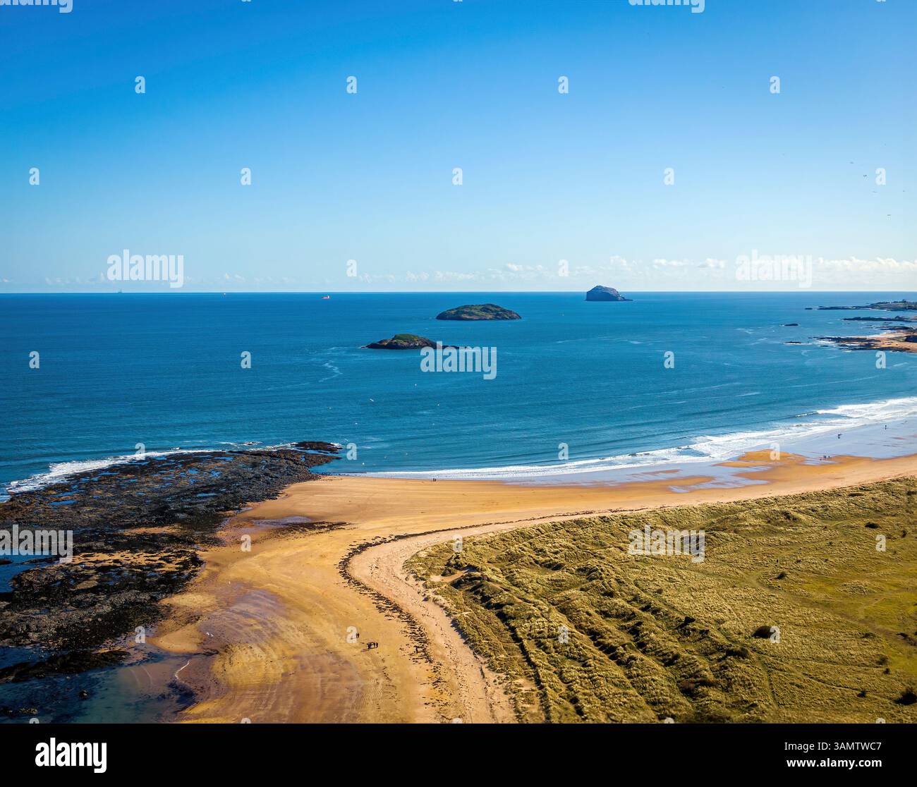 Aerial view of sandy beach and ocean with Bass Rock, Craigleith, and ...