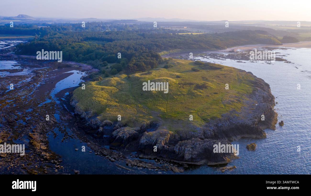 Aerial view of remote rocky shoreline with green hill and island, North ...