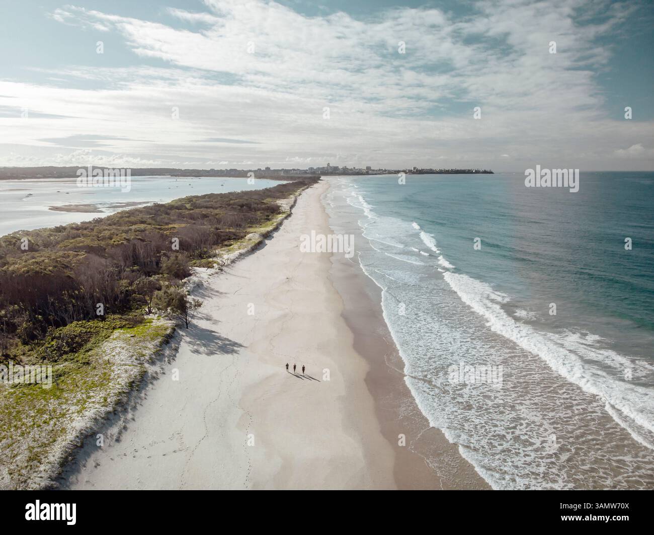 Aerial view of people walking on the beach with the city of Caloundra ...