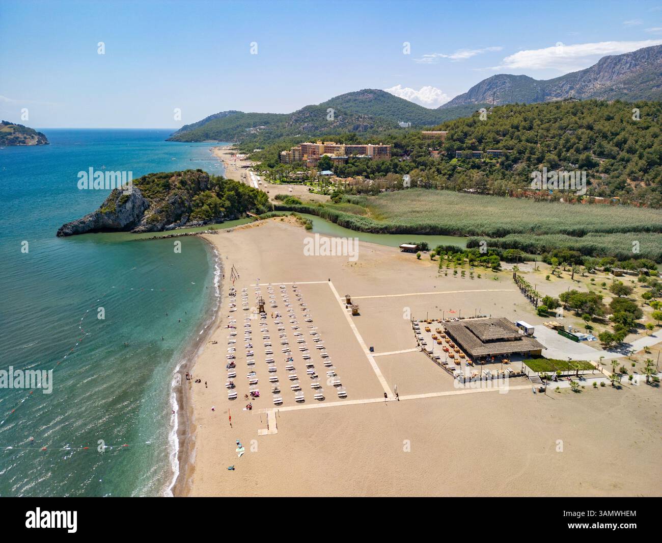 Aerial view of sandy beach and turquoise sea with mountainous backdrop ...