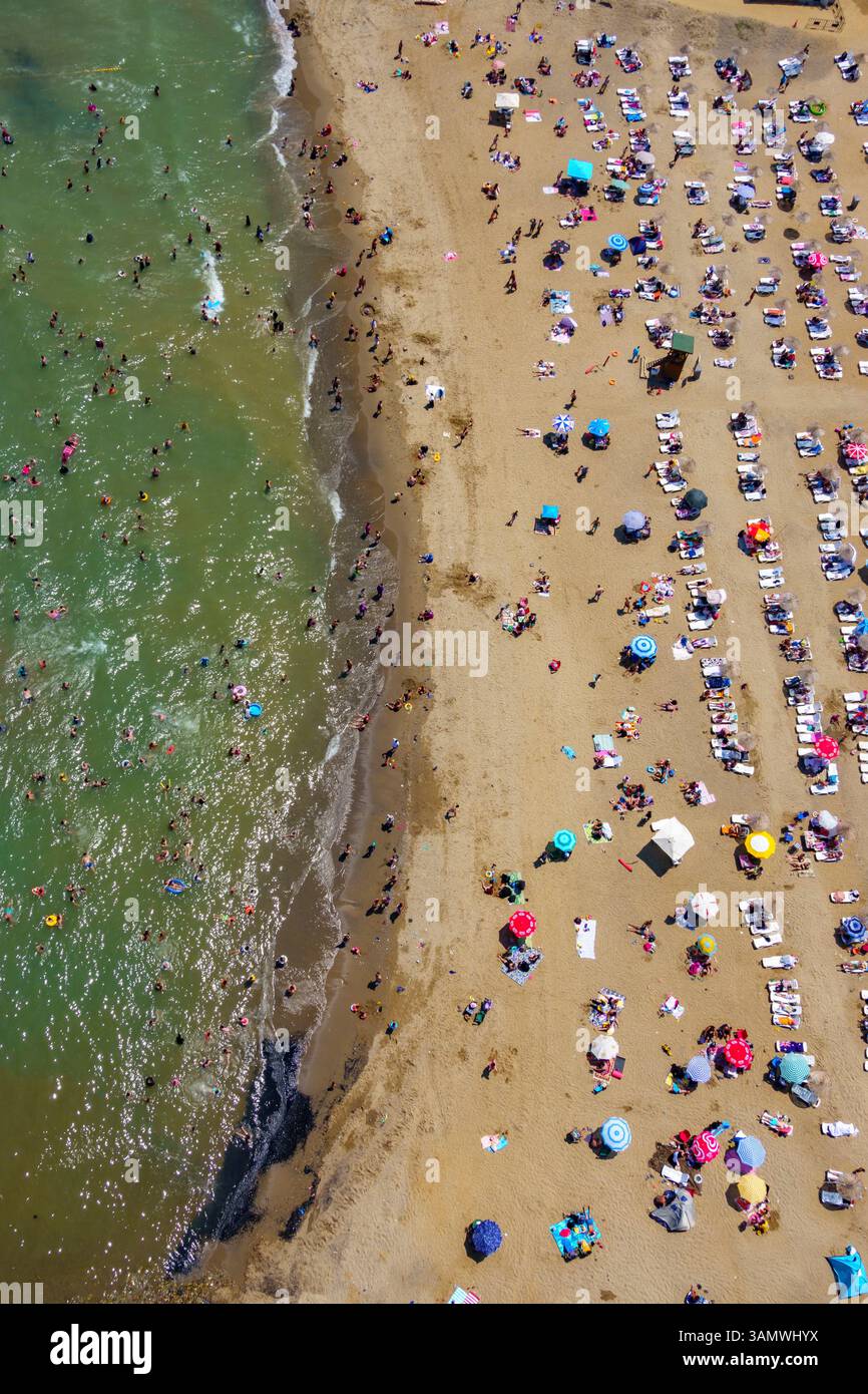 Aerial view of a crowded beach with sunbathers and colorful umbrellas ...