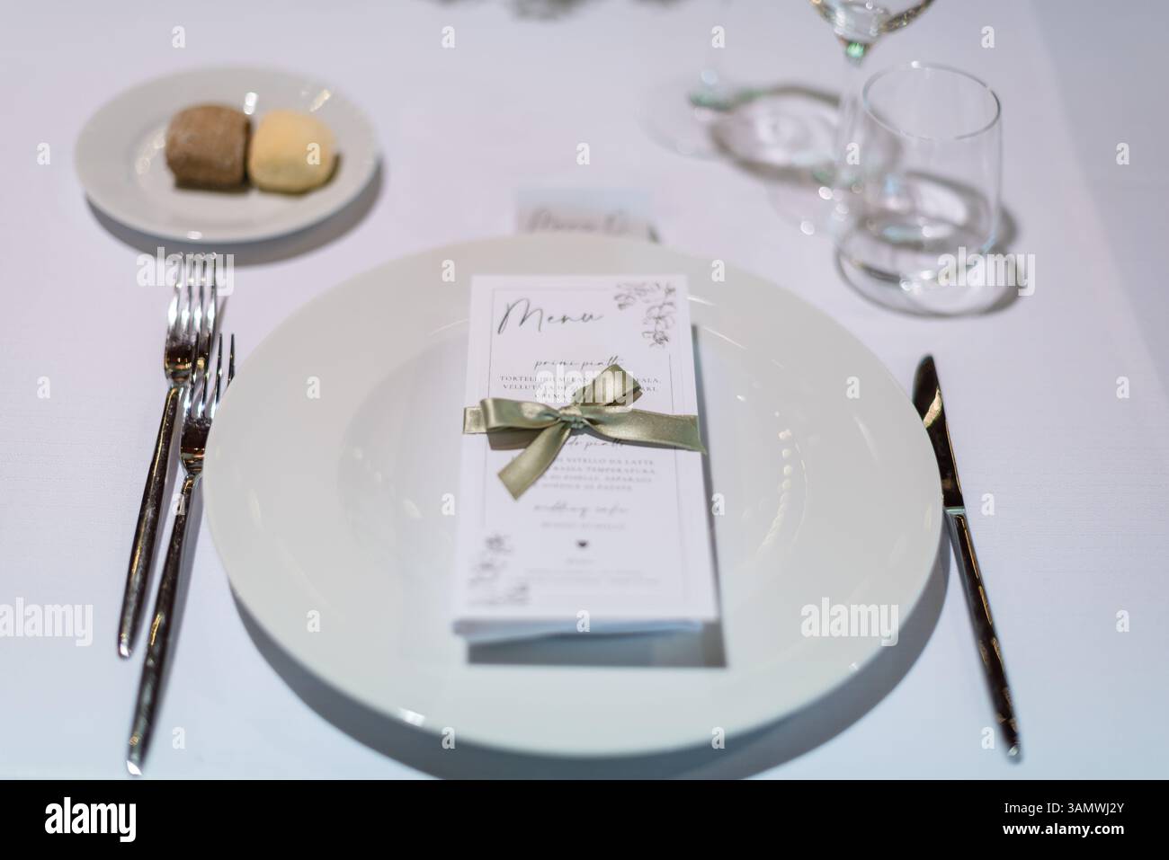 A beautifully arranged table with fine cutlery and a menu card tied ...