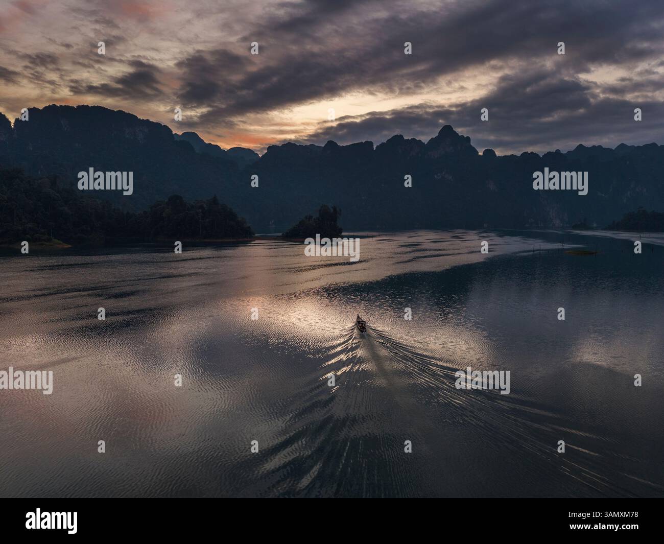 Aerial view of Cheow Larn Lake at sunrise surrounded by lush rainforest and mountains with a ...