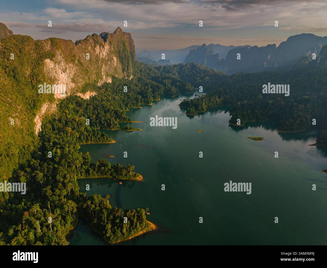 Aerial view of Cheow Larn Lake at sunrise surrounded by lush rainforest ...