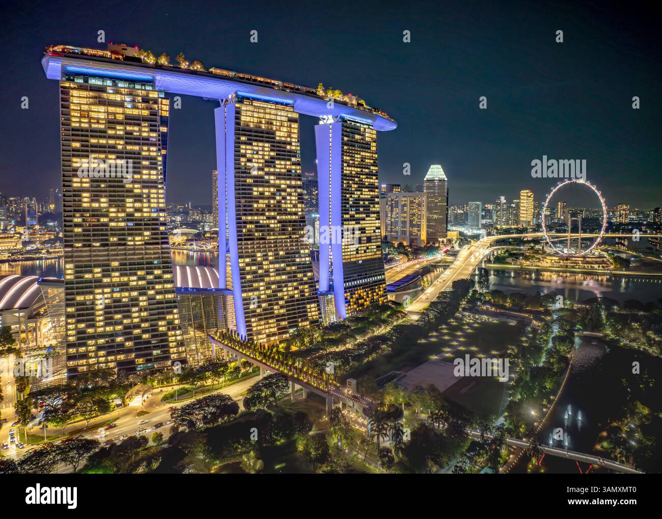 Aerial view of glowing marina bay sands and super trees at night with singapore flyer in ...