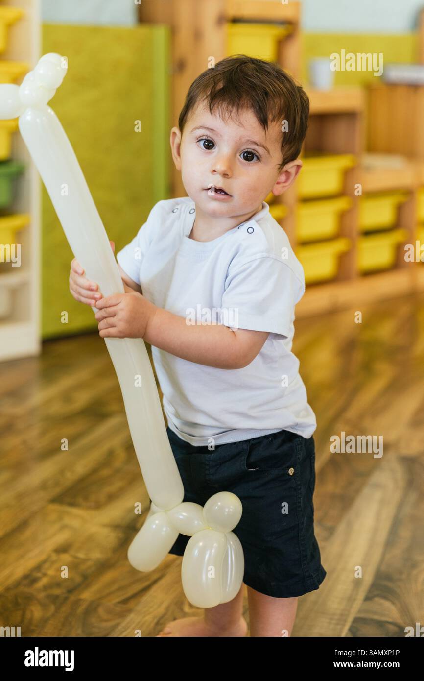 Toddler boy holding inflated giraffe balloon animal in playroom Stock ...