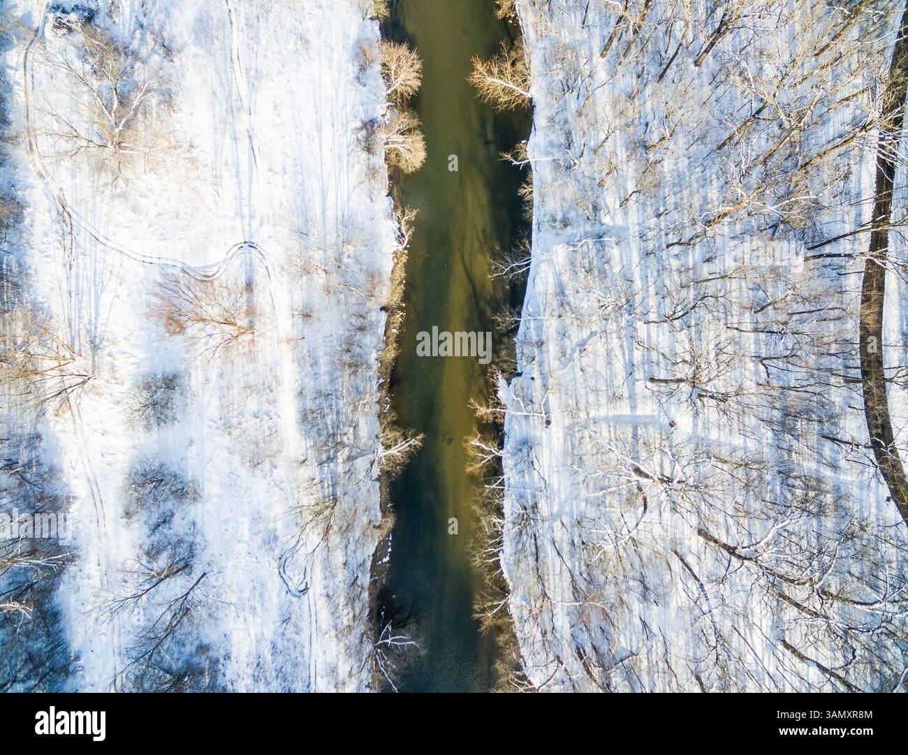 Aerial view of a small river crossing white and fresh snow landscape ...