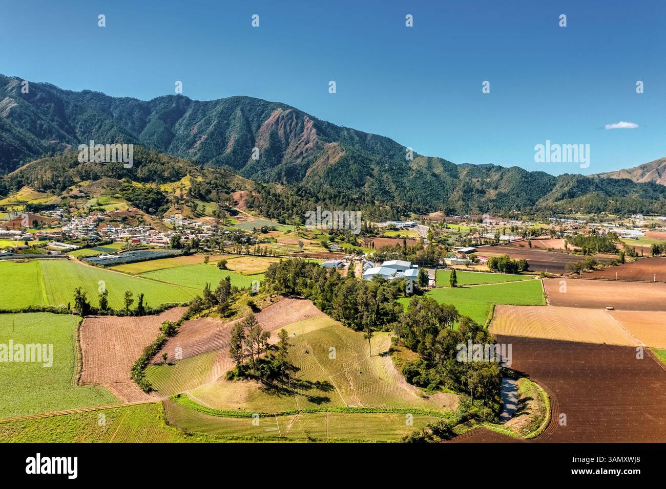 Aerial view of large mountains and agriculture under a clear sky in the ...