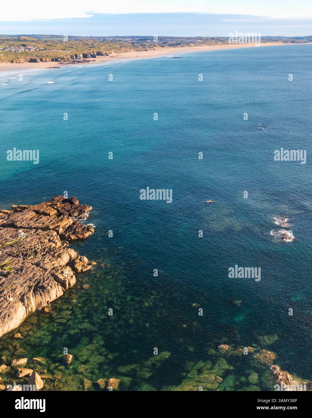 Aerial view of rocky coast with surfers and paddle boarders, Cornwall ...