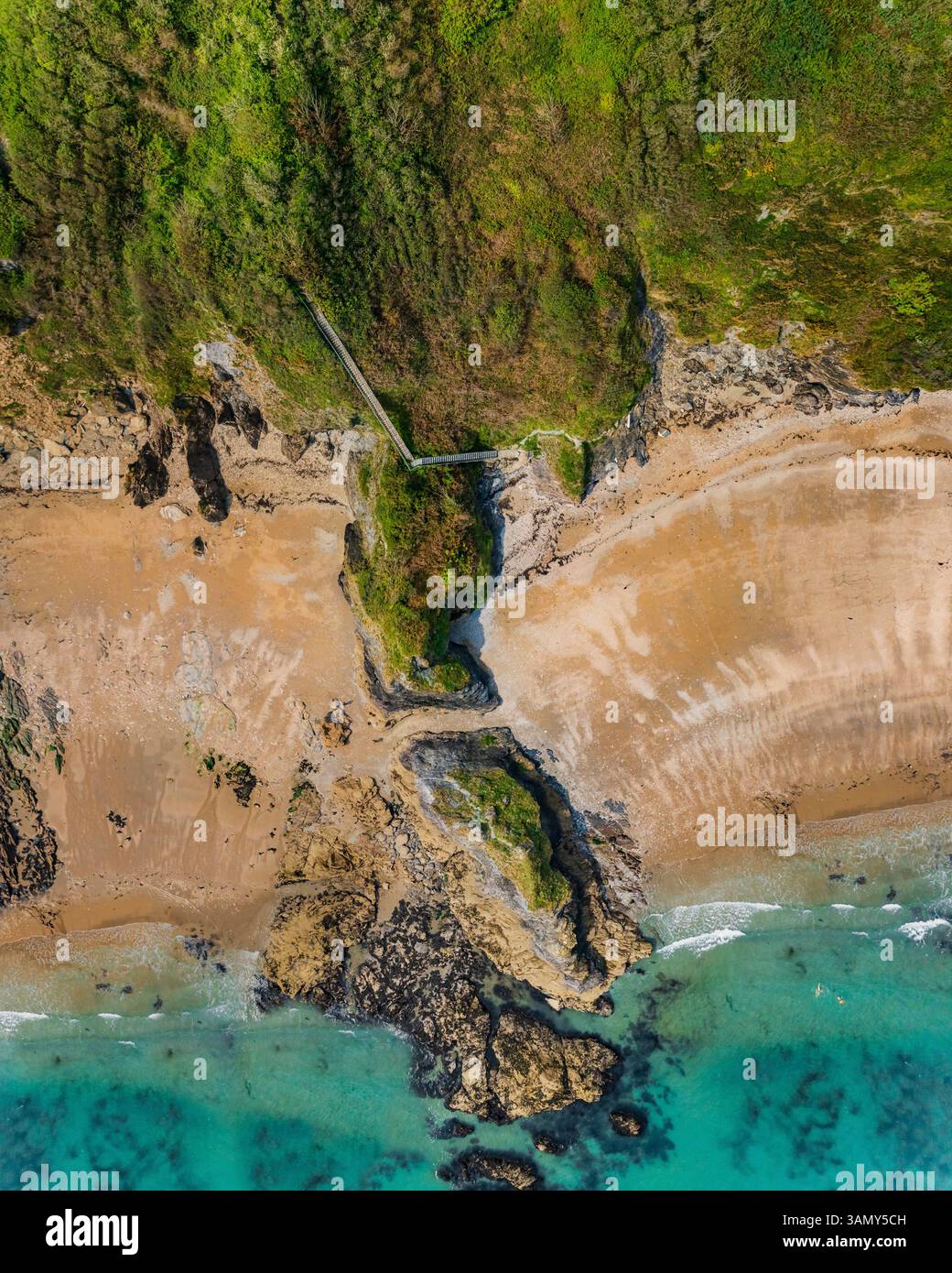 Aerial view of woodland steps down to Polstreath Beach with turquoise ...