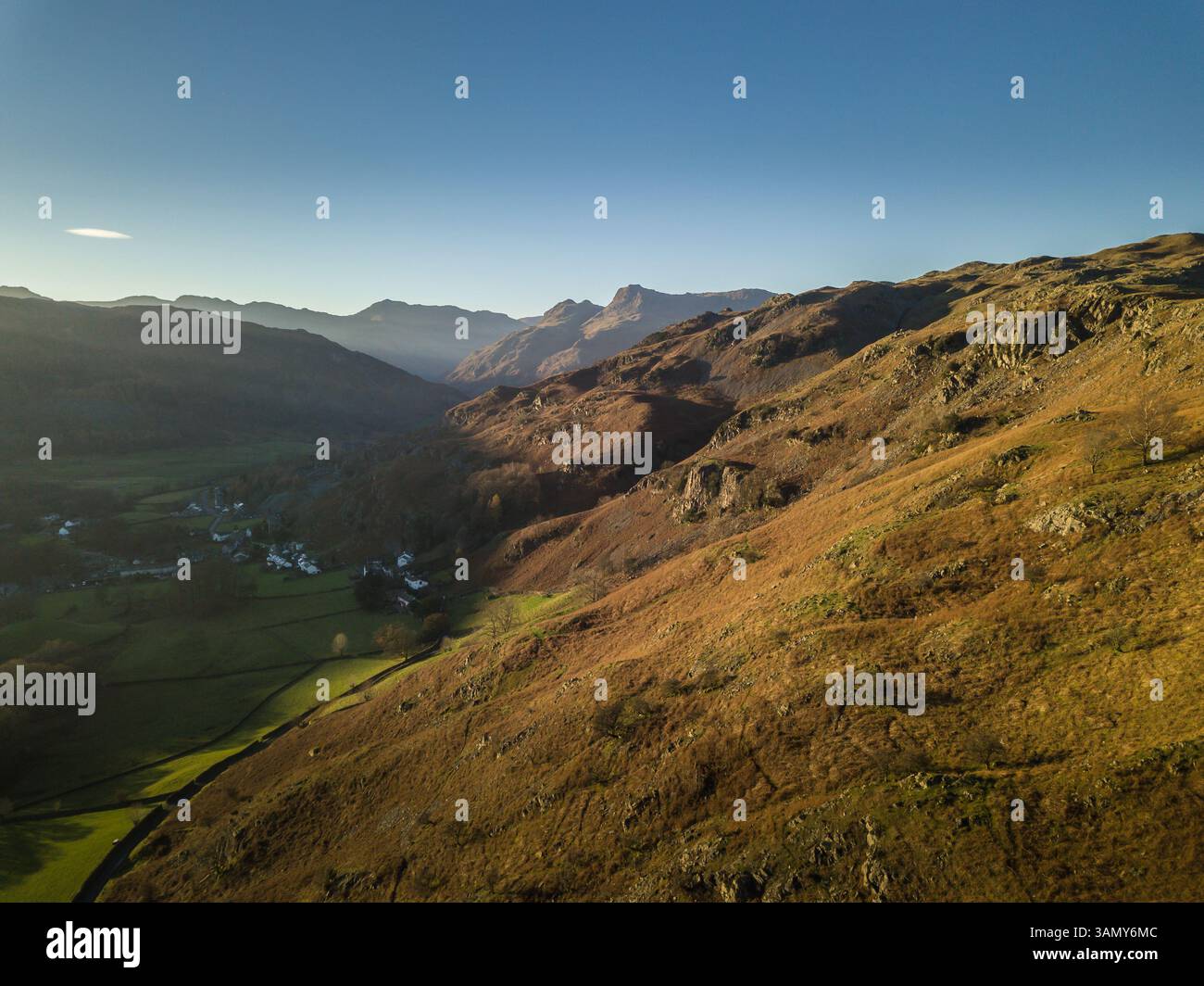 Aerial view of large mountains surrounding a village in Elterwater ...
