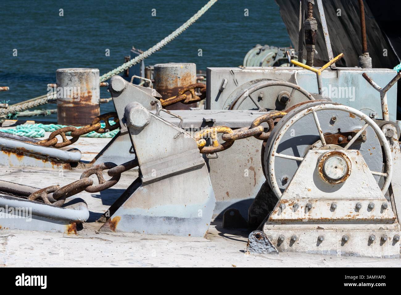 Rusty anchor chain and capstan on a ship's deck with bollards in ...