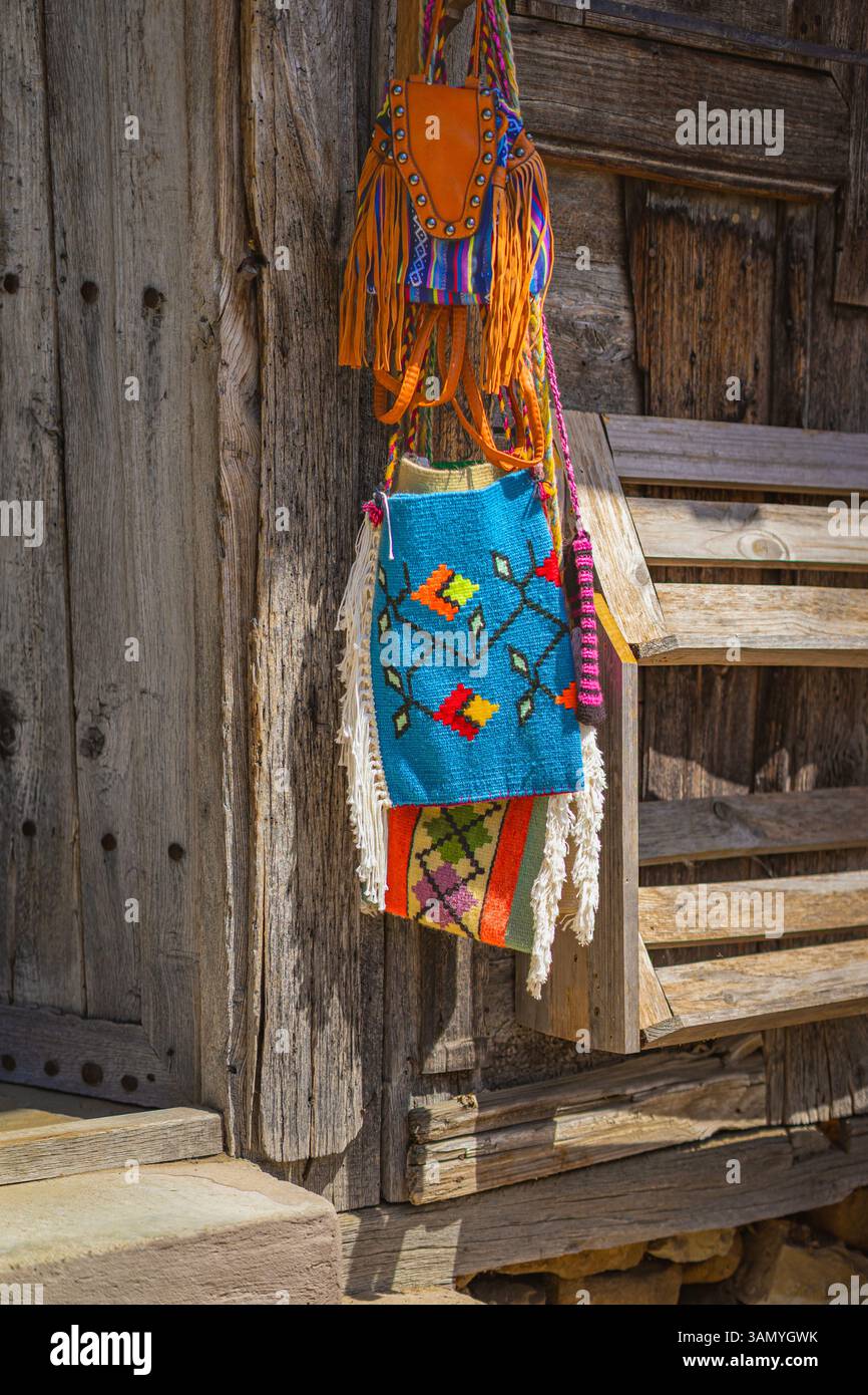Colorful ethnic bags hanging on rustic wooden wall. Traditional boho ...