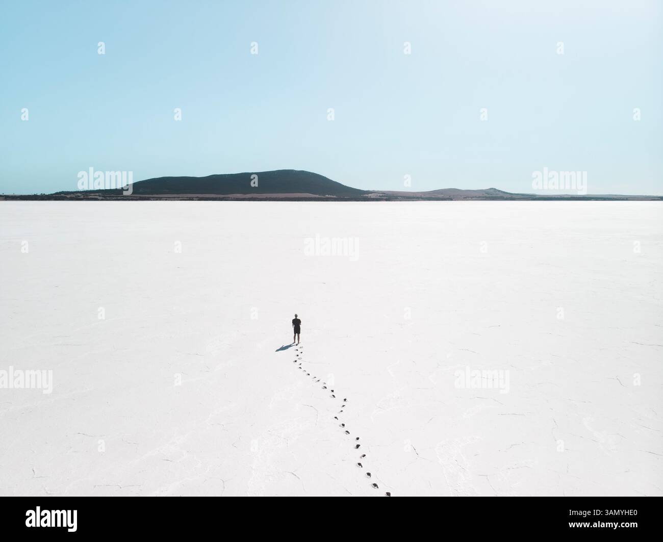 Aerial view a person standing on an empty salt flat with footprints ...