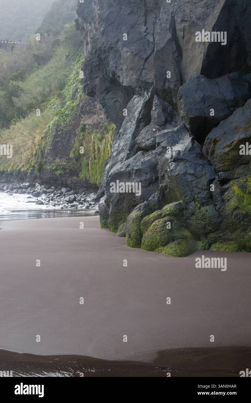 Seixal Port Beach features striking black sand and a backdrop of rugged ...