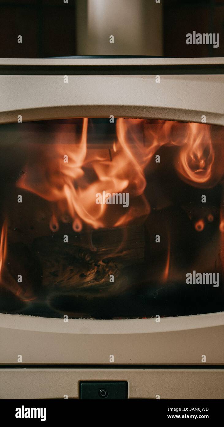 A stove with a fire burning inside. The fire is orange and yellow. The ...